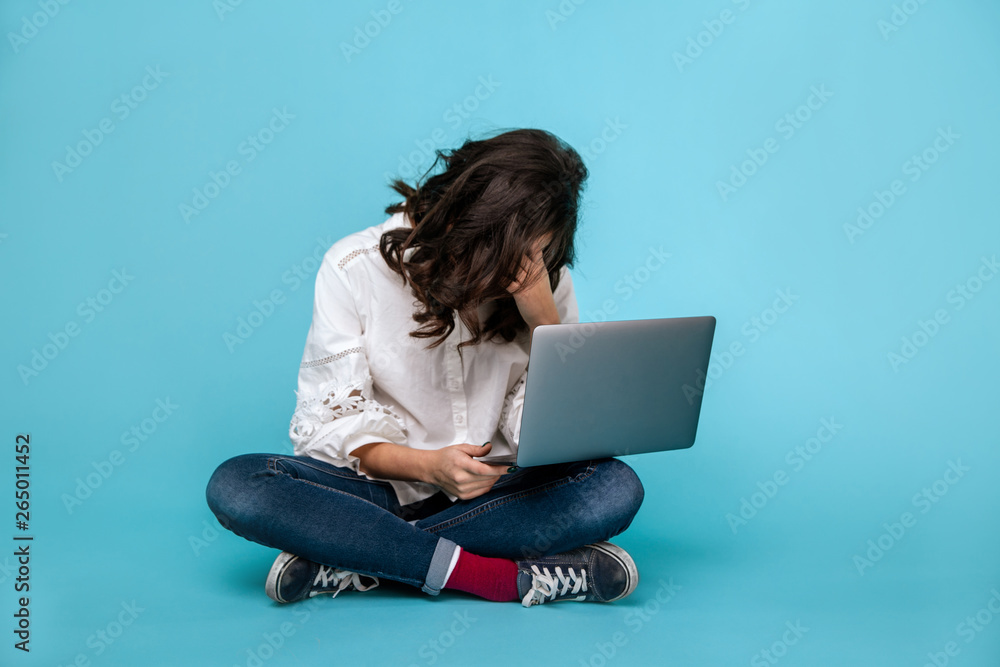 Sad girl with laptop sitting on the flour and feeling upset Stock Photo ...