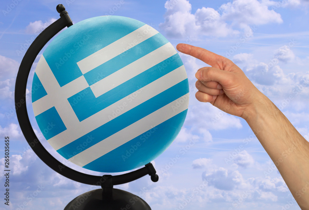 The index finger of a male hand points to a globe with a colored ...