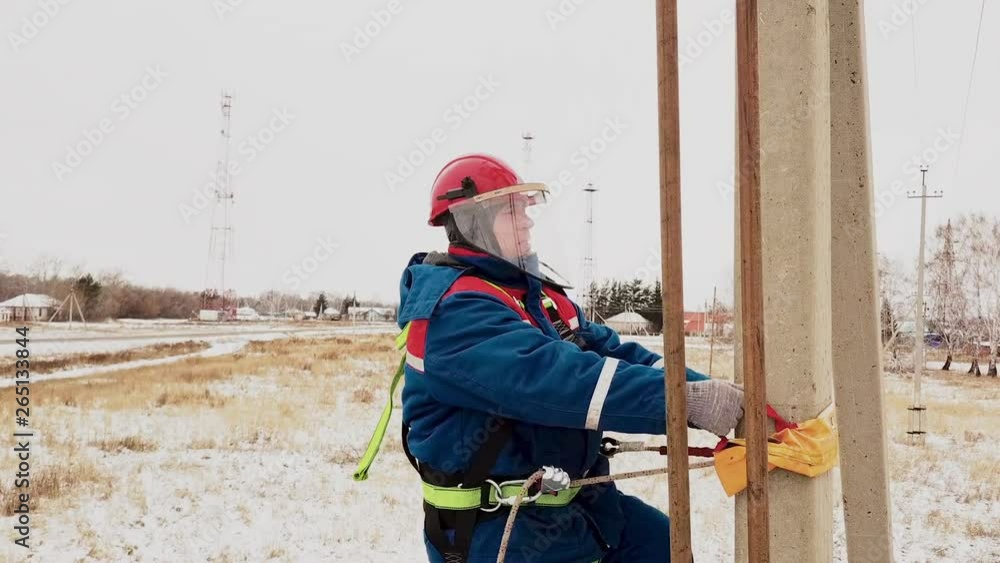 Electrician in helmet elevated to power line using belt at pole for ...
