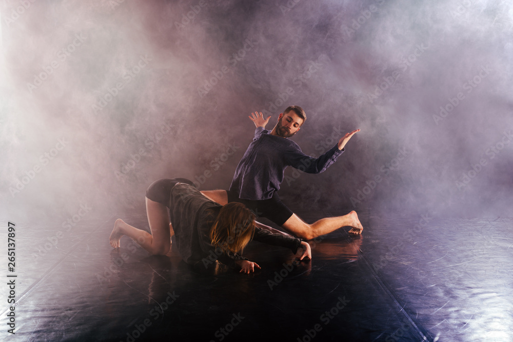 Modern dance couple twisting their legs and lening close to the ground ...