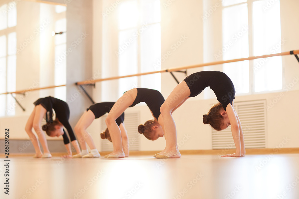 Full length portrait of group of little girls doing gymnastics in ...