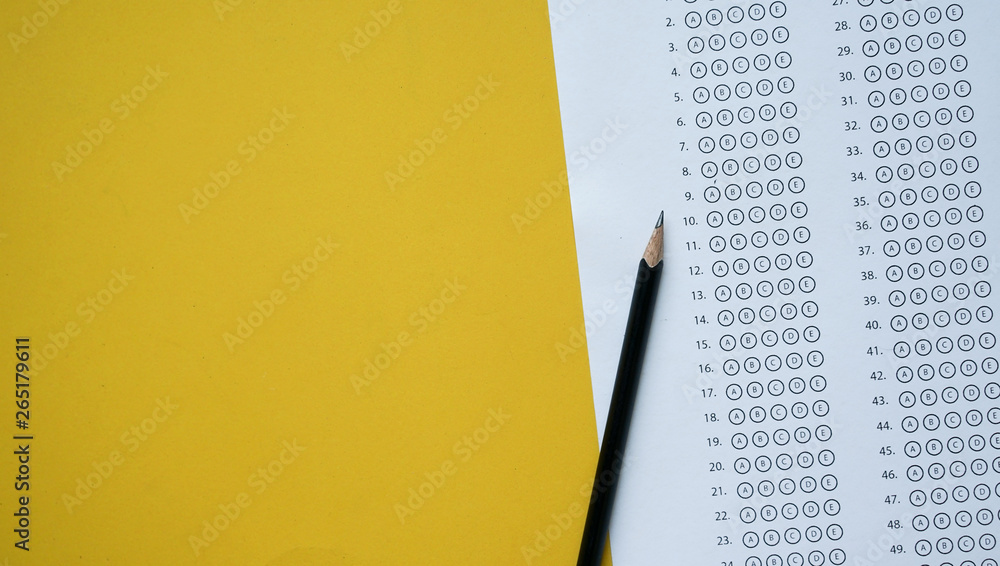 close up top view of black pencil over exam answer sheet paper with ...