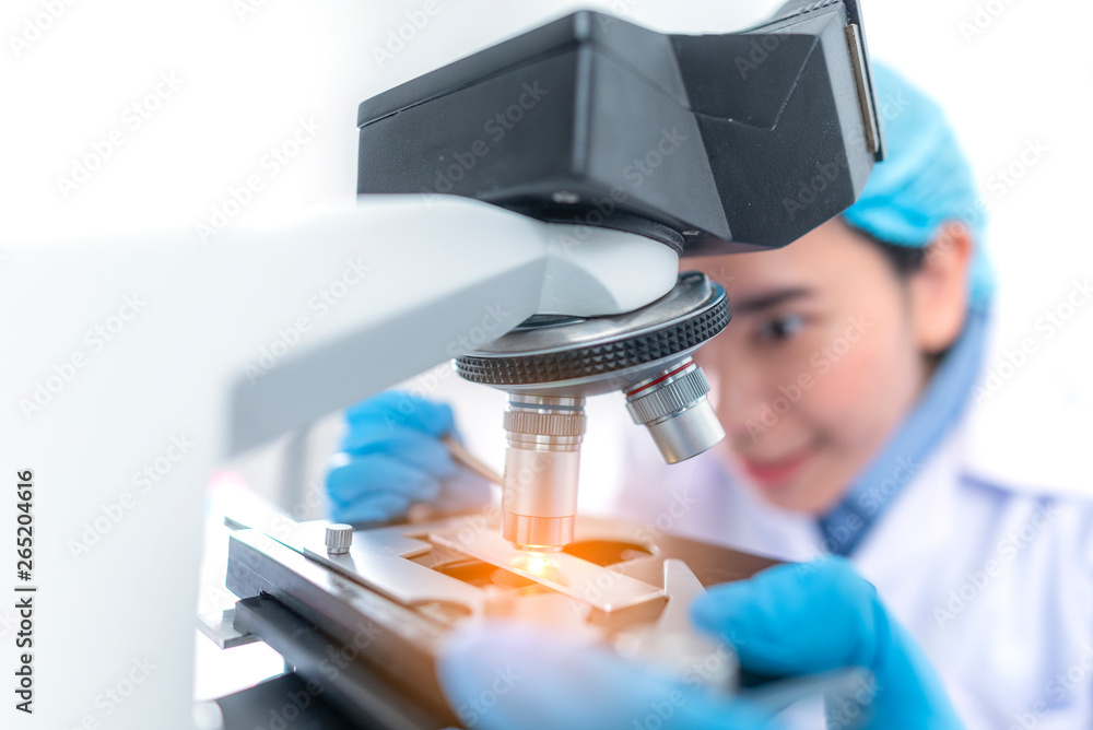 Scientist analyzing microscope slide at laboratory. Young woman ...