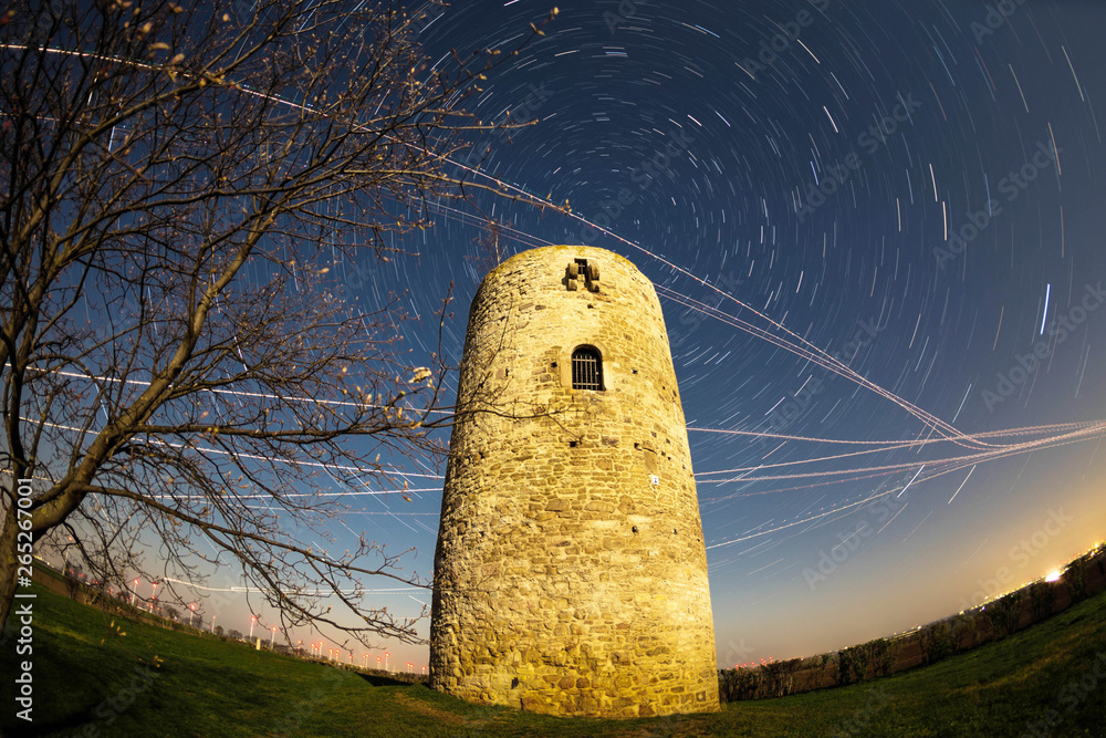 Night view of ancient watchtower in moonlight with start trails and ...