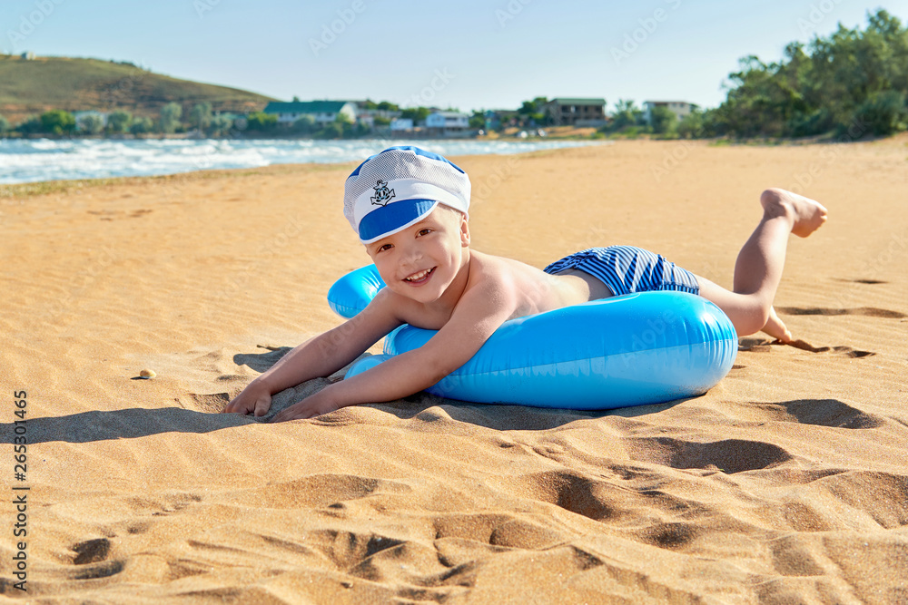 Funny child lying on sand beach, inflatable ring on sunny day. Cute ...