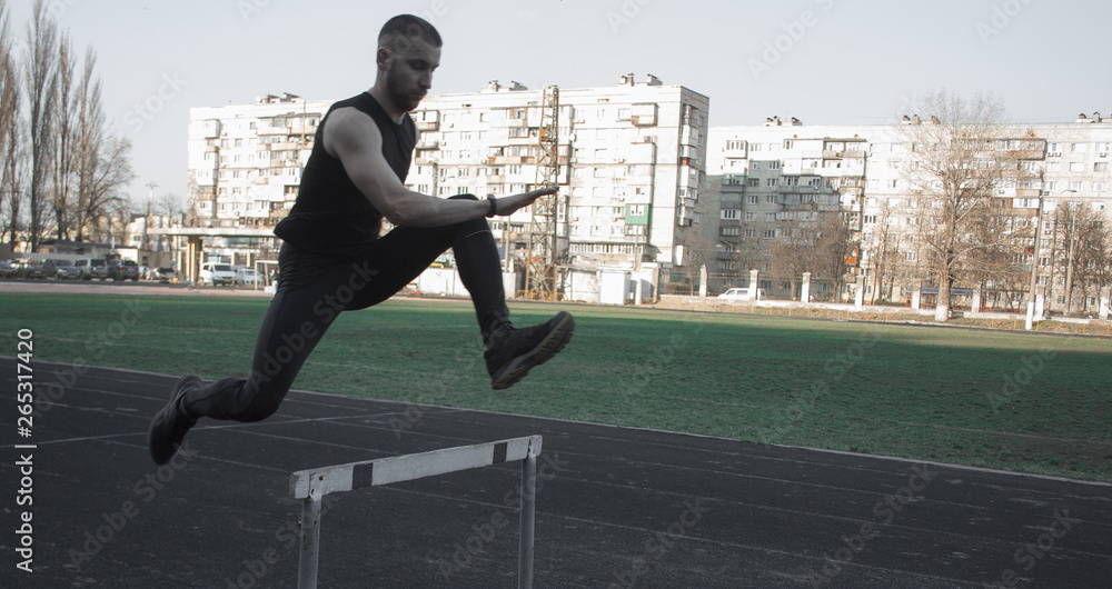 one caucasian male in a jump over a barrier. running on the stadium ...