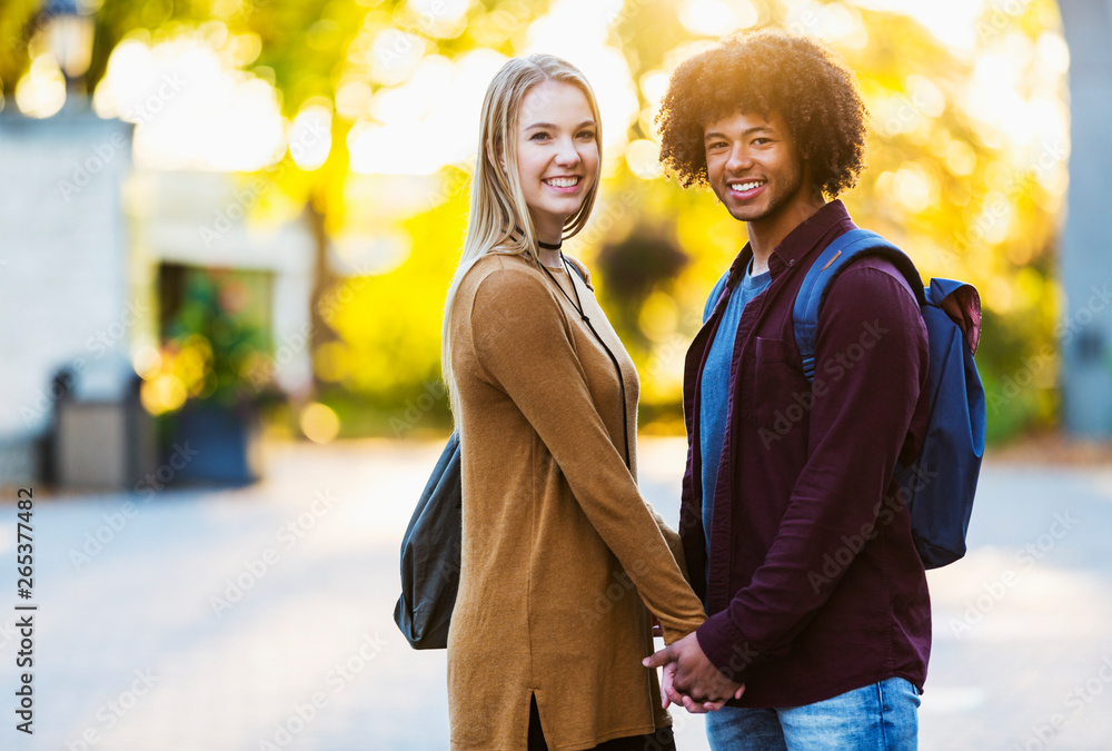 Boyfriend and girlfriend standing and holding hands on the university ...