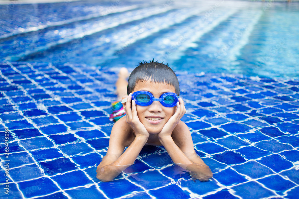 cute little boy feel happy play and swimming at swimming pool , sunny ...