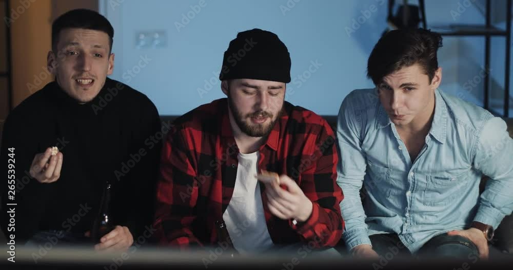 Three football fans are rooting for their favorite football team at ...