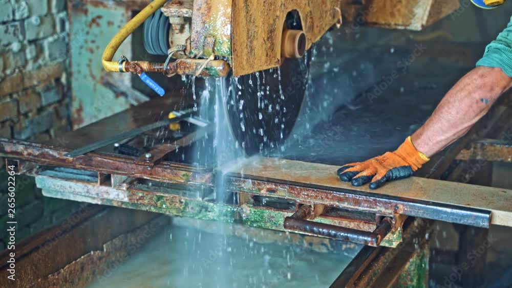 Automated circular saw cuts the stone slab at industrial factory ...