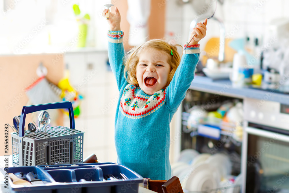 Cute little toddler girl helping in the kitchen with dish washing ...