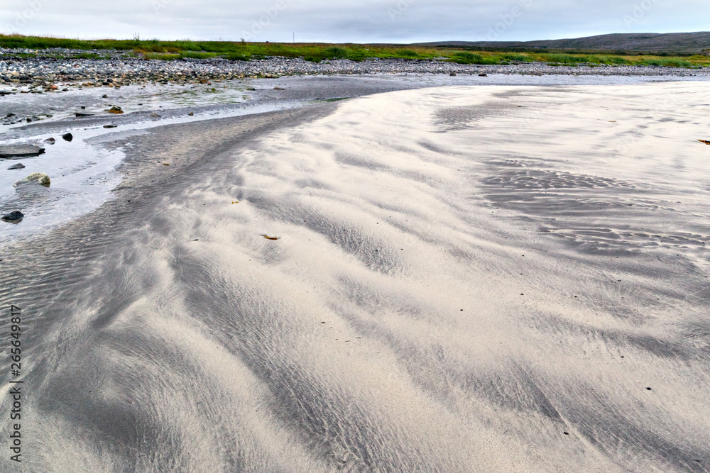 Patterns of black and yellow sand in the tidal zone on the beach of the ...