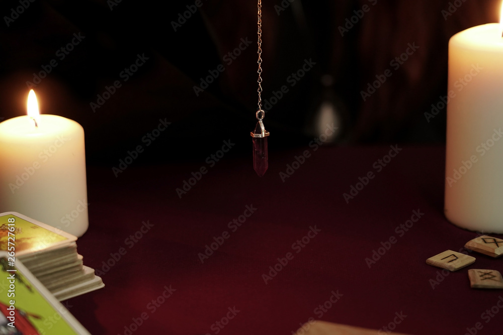 Tarot cards, amethyst magic stone pendulum on a chain, white candles ...