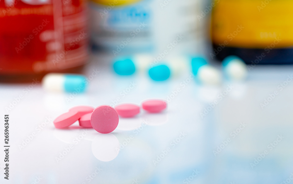 Round pink tablets pill on blurred background of drug bottle ...
