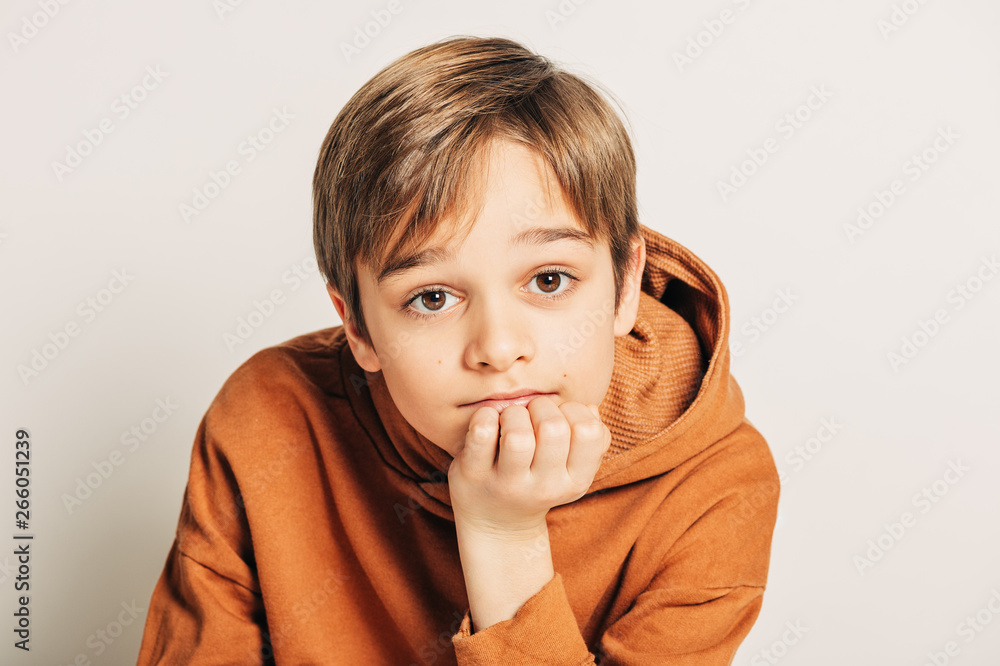 Studio shot of handsome 10 year old boy with blond hair, wearing brown ...