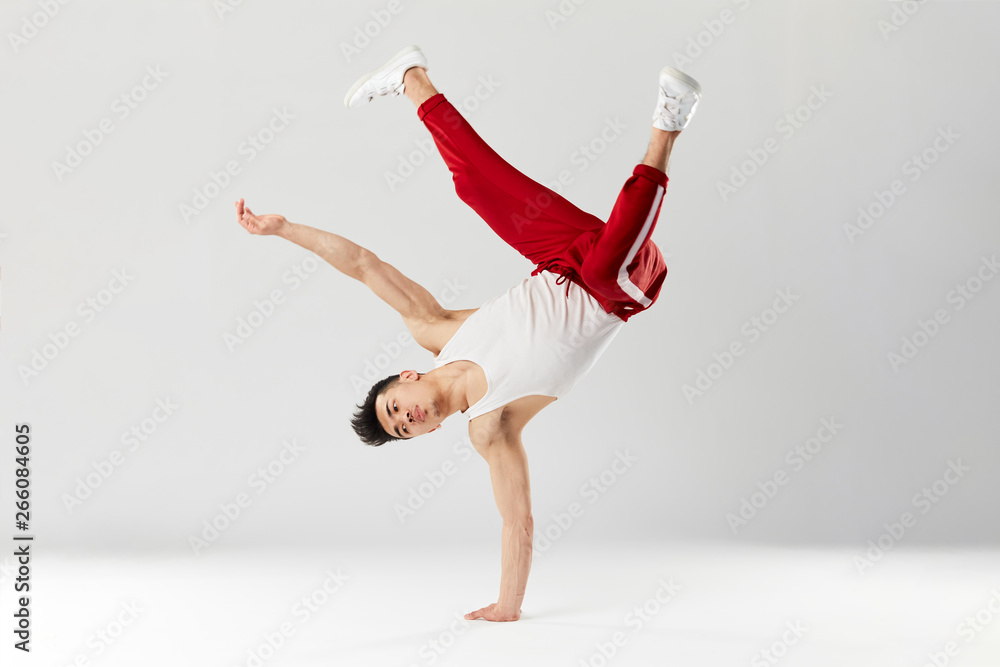 Athletic young b-boy standing on one hand while dancing break dance and ...