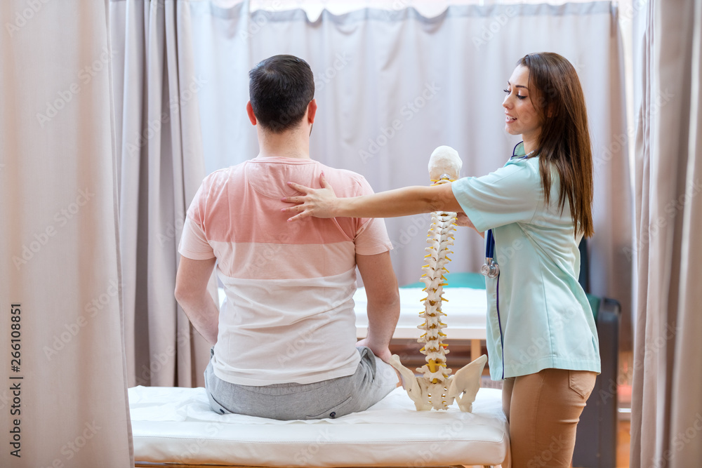 Beautiful female doctor with brown hair holding spine model and ...