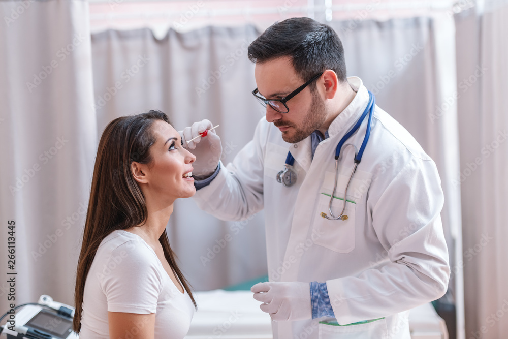 Doctor with serious facial expression taking sample with swab from the ...