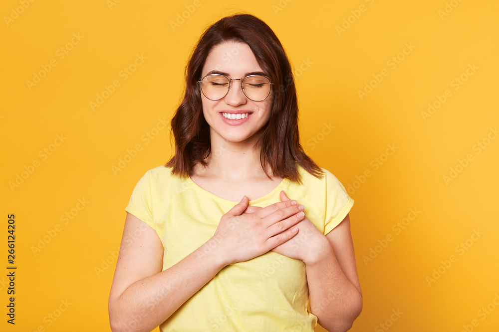 Image of charming woman keeps hands together on chest, expresses ...