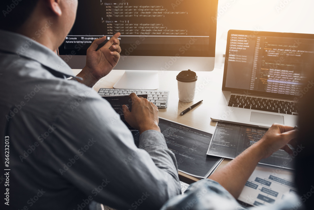 Two software developers are using computers to work together with their partner at the office ...