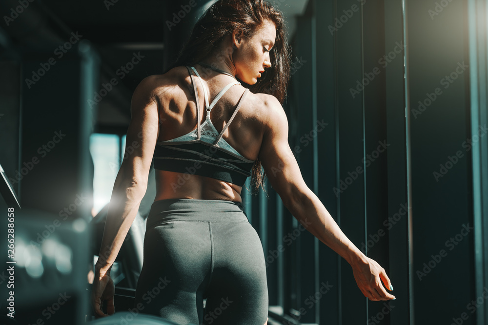 Portrait of beautiful Caucasian female bodybuilder posing in gym with ...