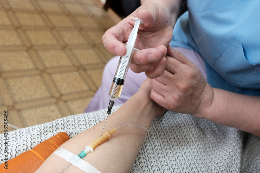 The nurse enters a medical syringe into the system of tubes in the hand ...