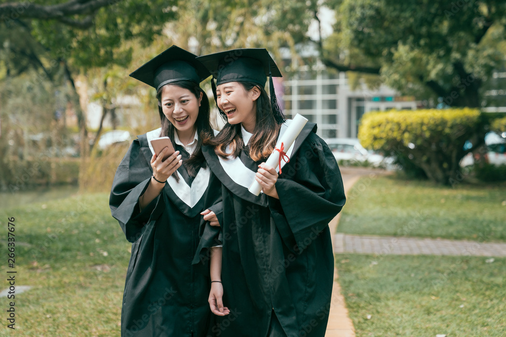Excited two asian female fresh graduates in gown and mortarboard ...