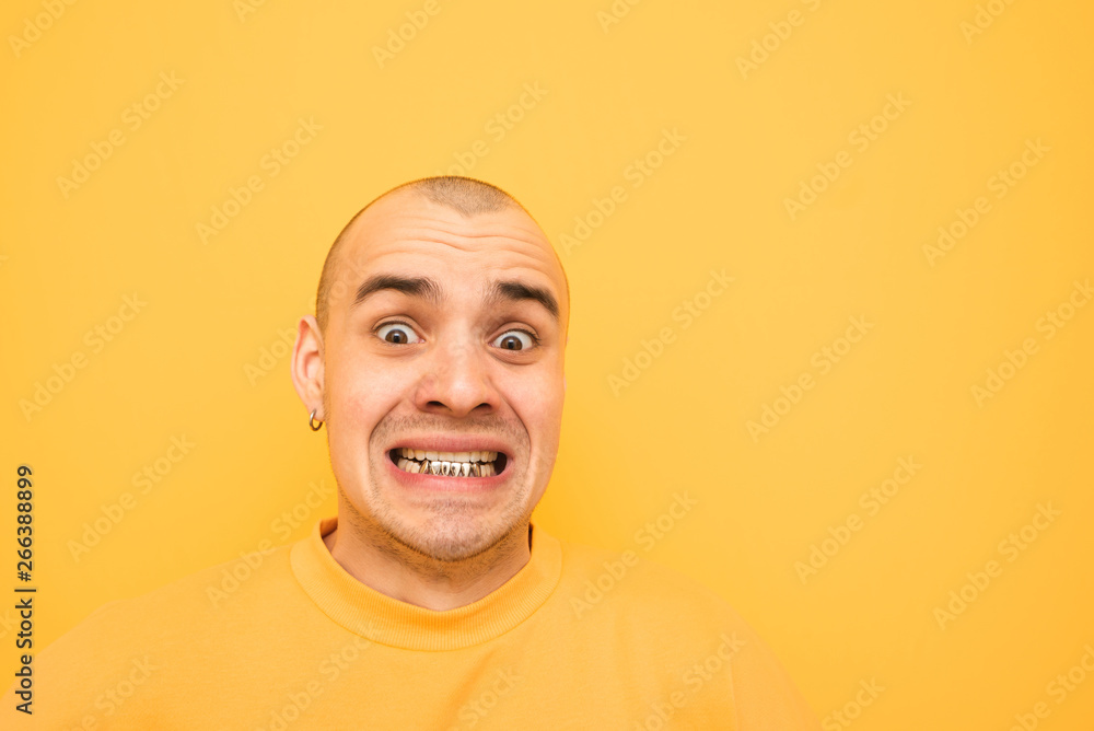 Сlose-гз portrait of the crazy guy from the grillz on his teeth makes a funny face and shocked ...