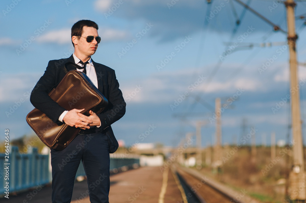 Stylish and rich businessman in glasses, in a suit and with a suitcase ...