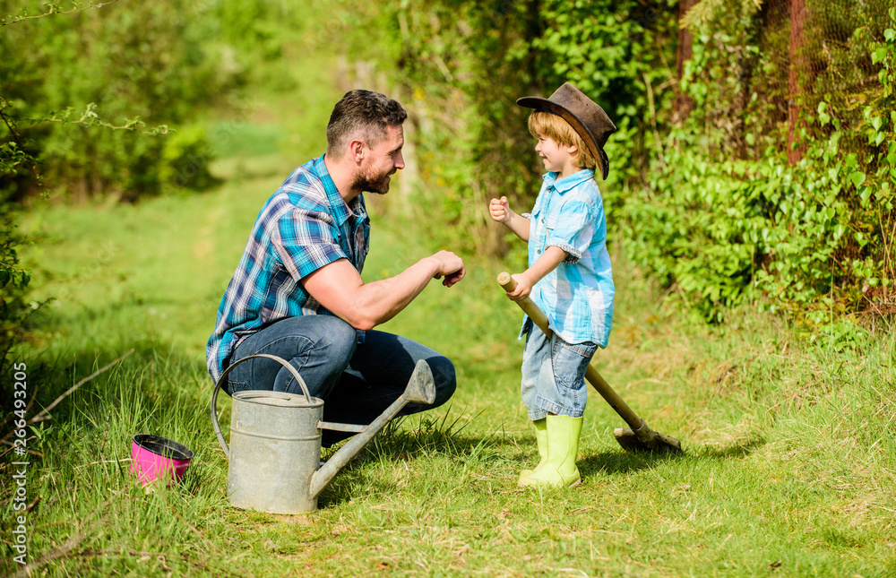 father and son in cowboy hat on ranch. Eco farm. small boy child help ...