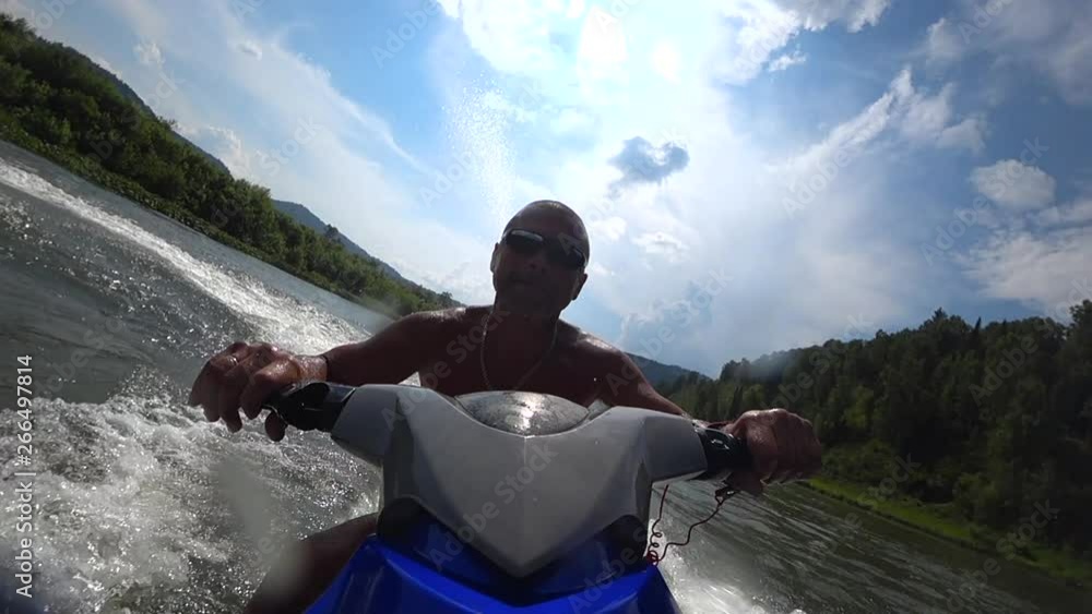 muscular guy rides on the river on a jet ski. riding a jet ski on a ...