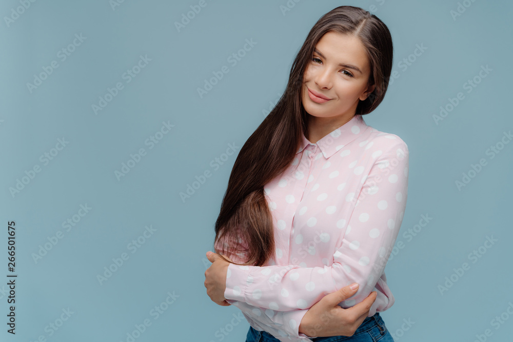 Portrait of good looking woman with long dark luxurious hair keeps ...