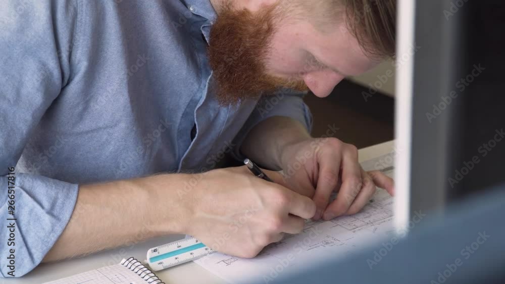 Civil engineer drawing blueprint plans indoors office working ...