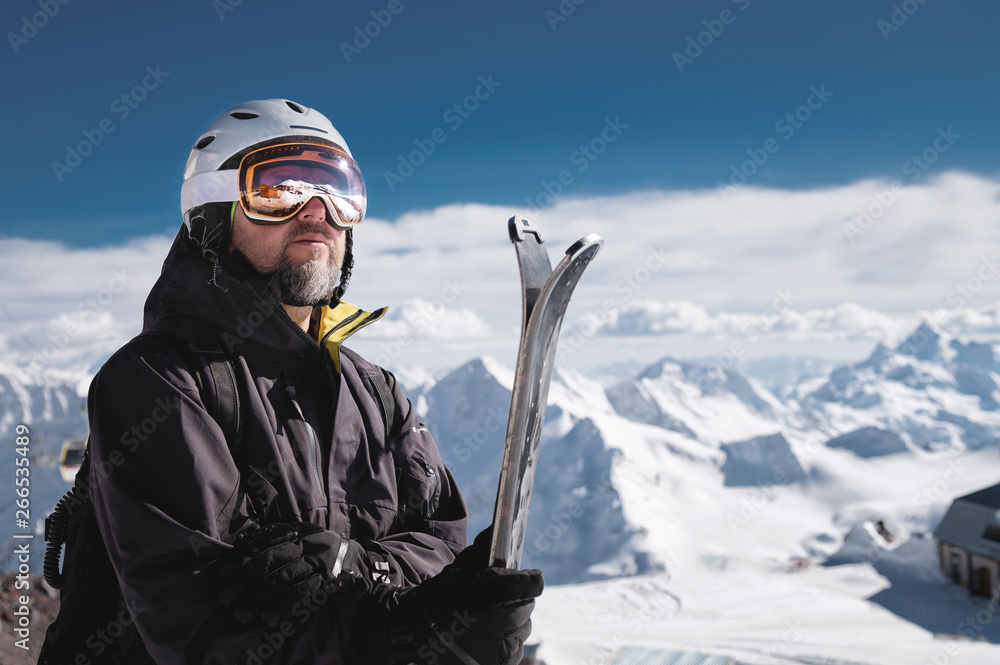 Portrait athlete skier in helmet and ski mask against the snow-capped ...