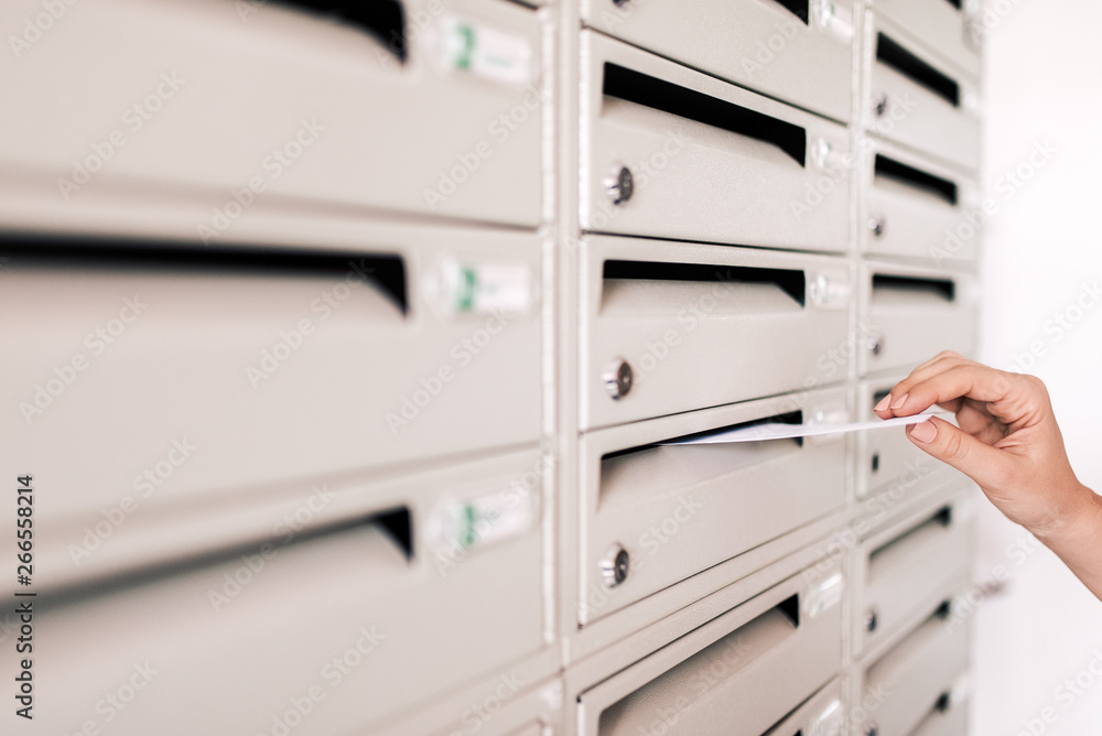 Sending mail. Putting letters in apartment building mailbox, close-up ...