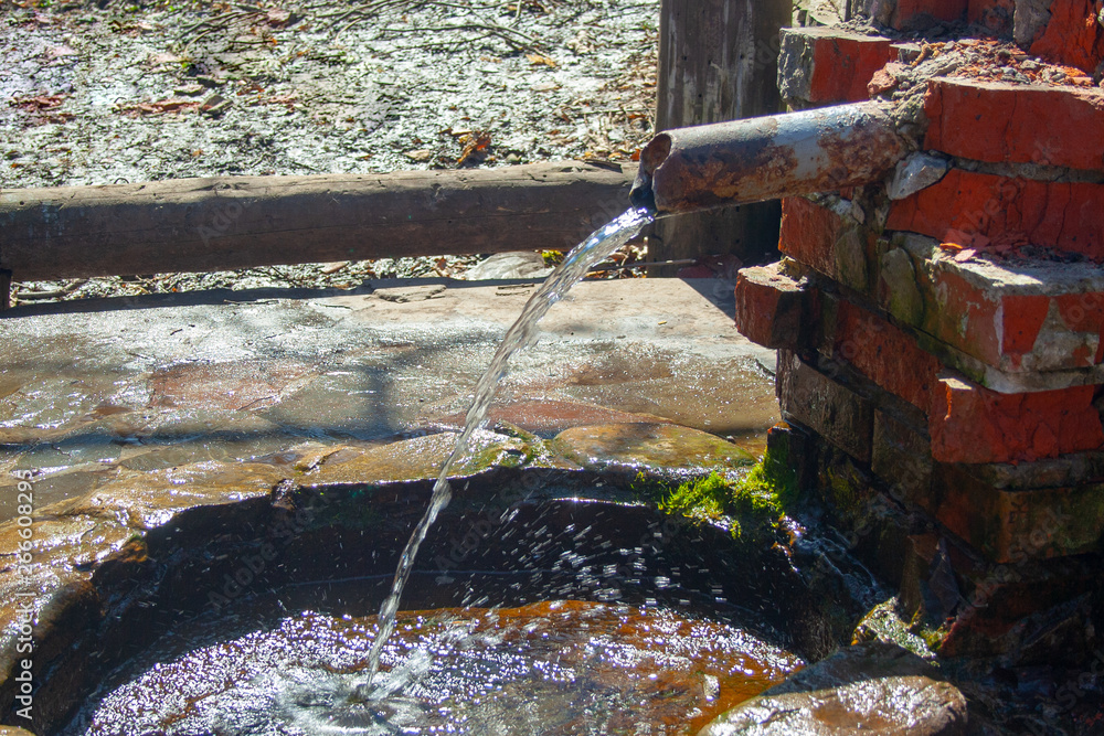 Natural spring folded of old bricks and metallic pipe. Clean fresh ...