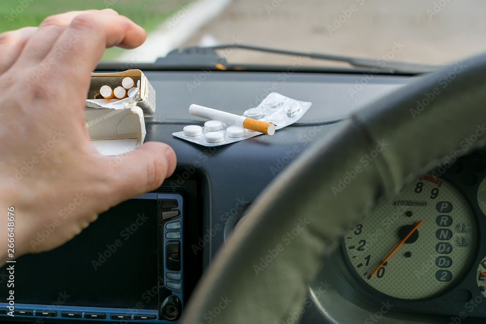 the hand of the person, the driver, takes a cigarette from the panel of ...