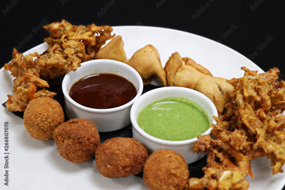 assorted indian snack pakora plater with paneer balls, onion crisps and ...