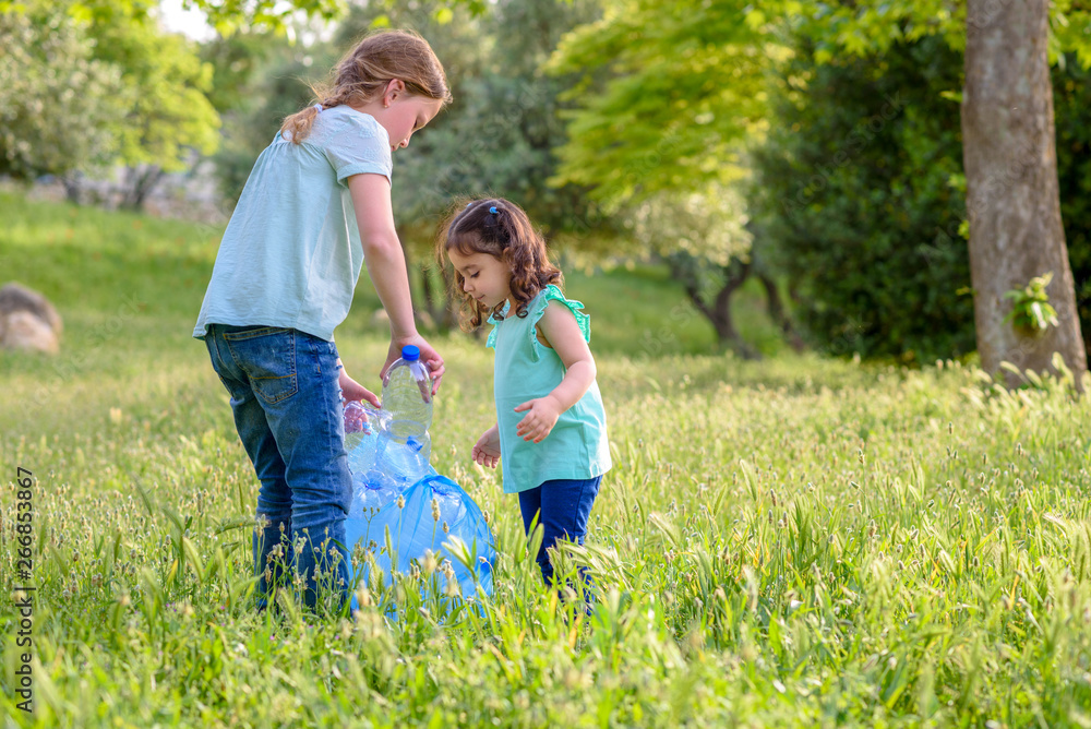 Cute little girls cleaning up plastic litter on grass. Children ...