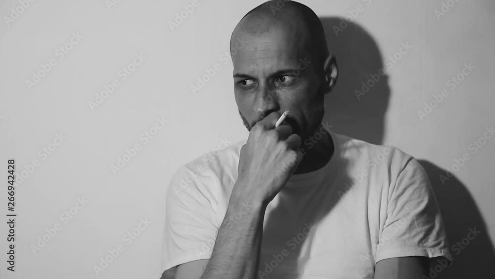 Young nervous smoker man smoking cigarette in cloud of smoke after ...