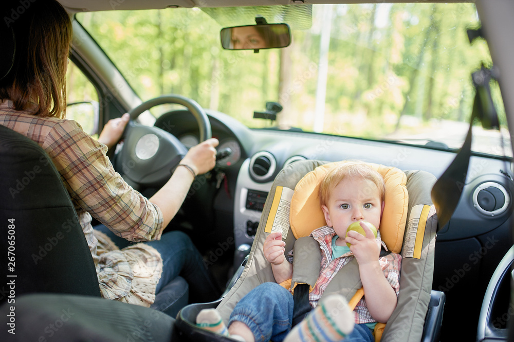 Young beautiful woman driving a car. On a front seat mounted child ...