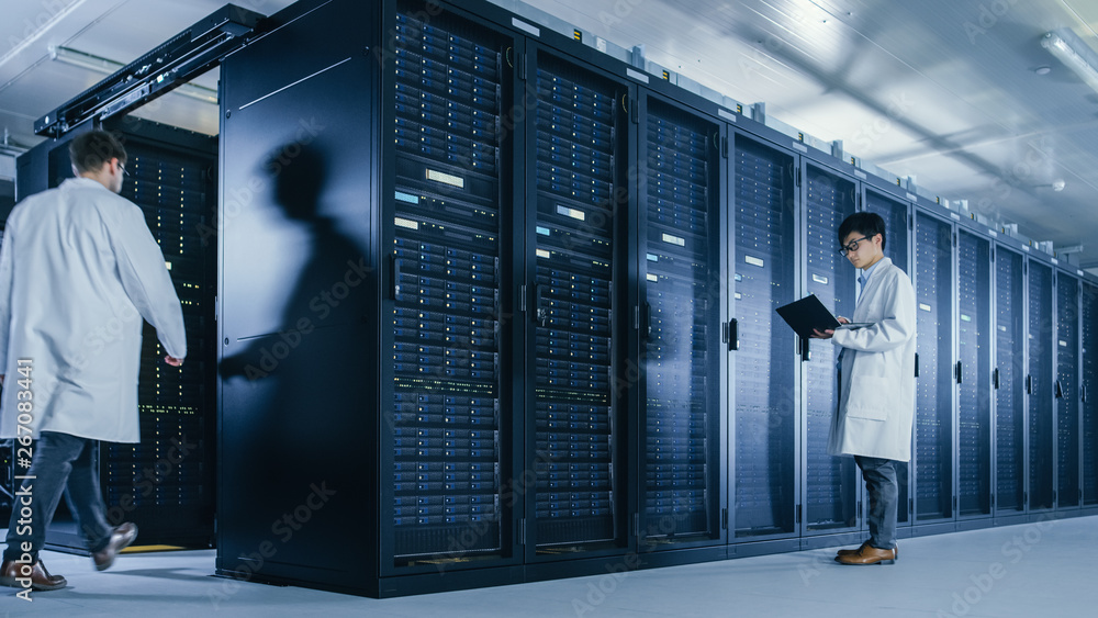 In Data Center: Male IT Technician Wearing White Coat Stands Beside ...