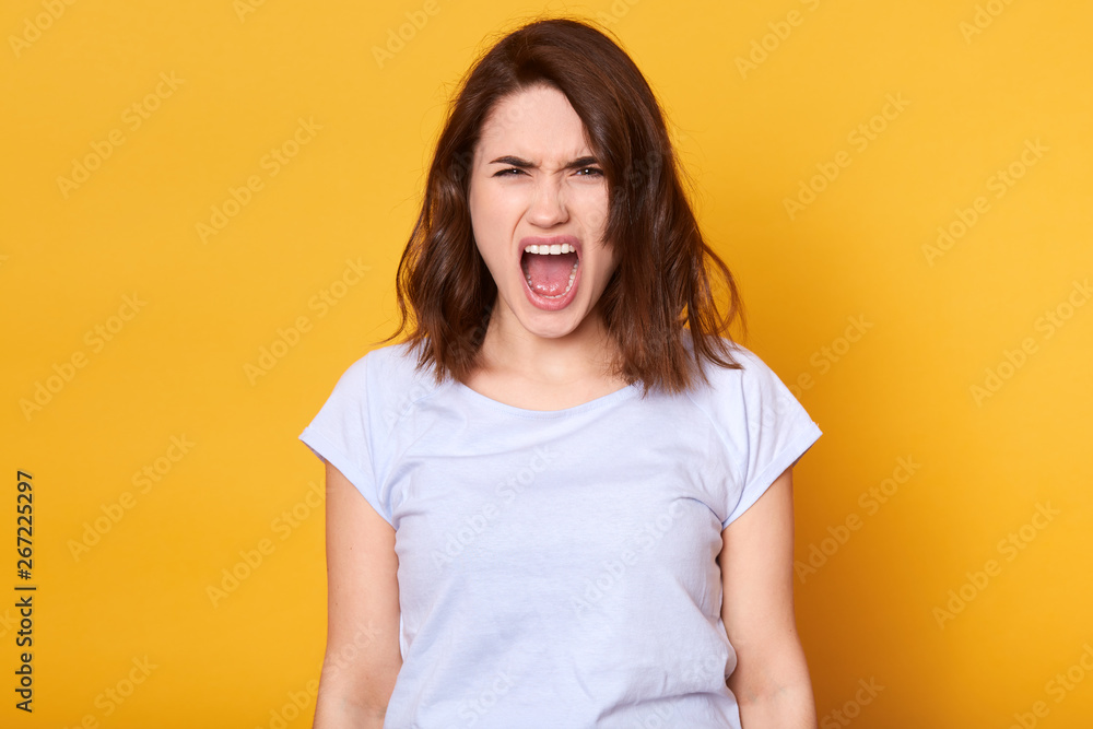Screaming emotional angry woman isolated over yellow studio background ...