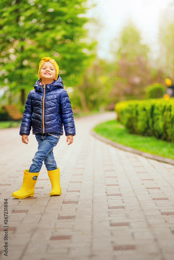 Little girl playing after the rain in the park. A cute children girl ...