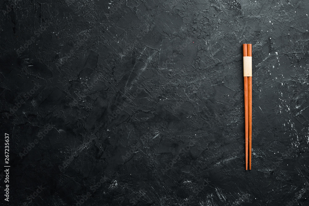 Wooden chopsticks on a black stone background. Top view. Free space for ...