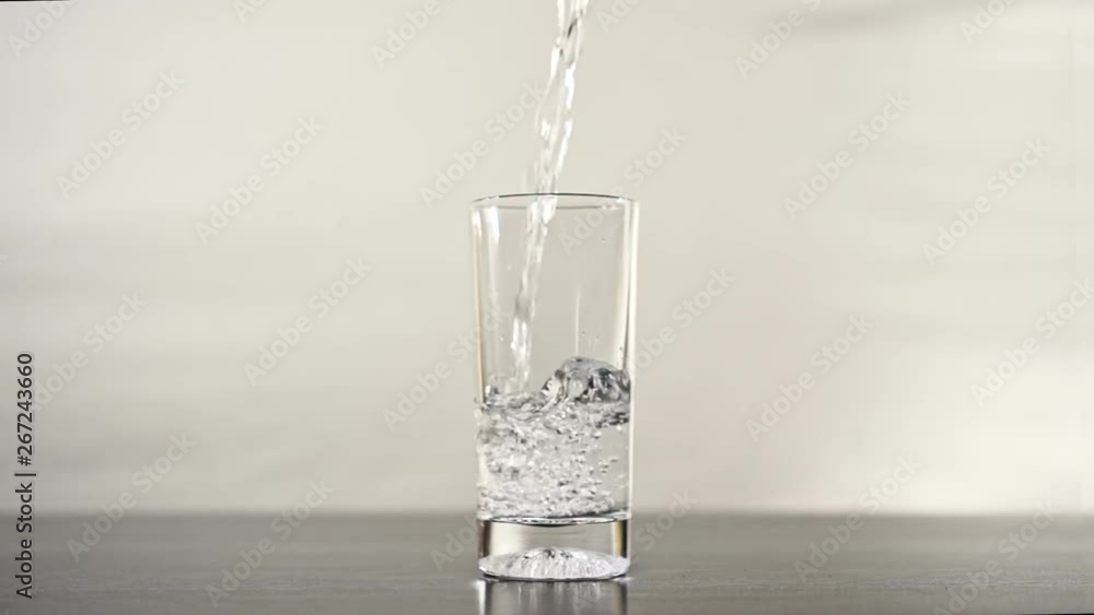 Pouring water into a glassPouring glass of water in slow motion. A tall ...