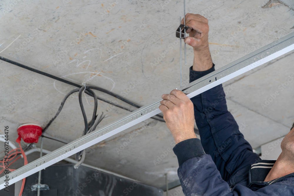 Construction worker assemble a suspended ceiling fixing metal frame ...