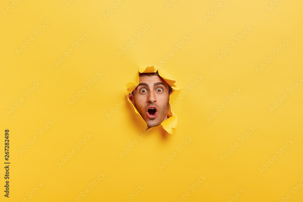 Surprised young man with bristle keeps mouth widely opened, stares ...