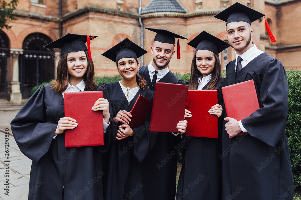 Happy graduation day. 5 graduates hold his graduate red diplomas in ...