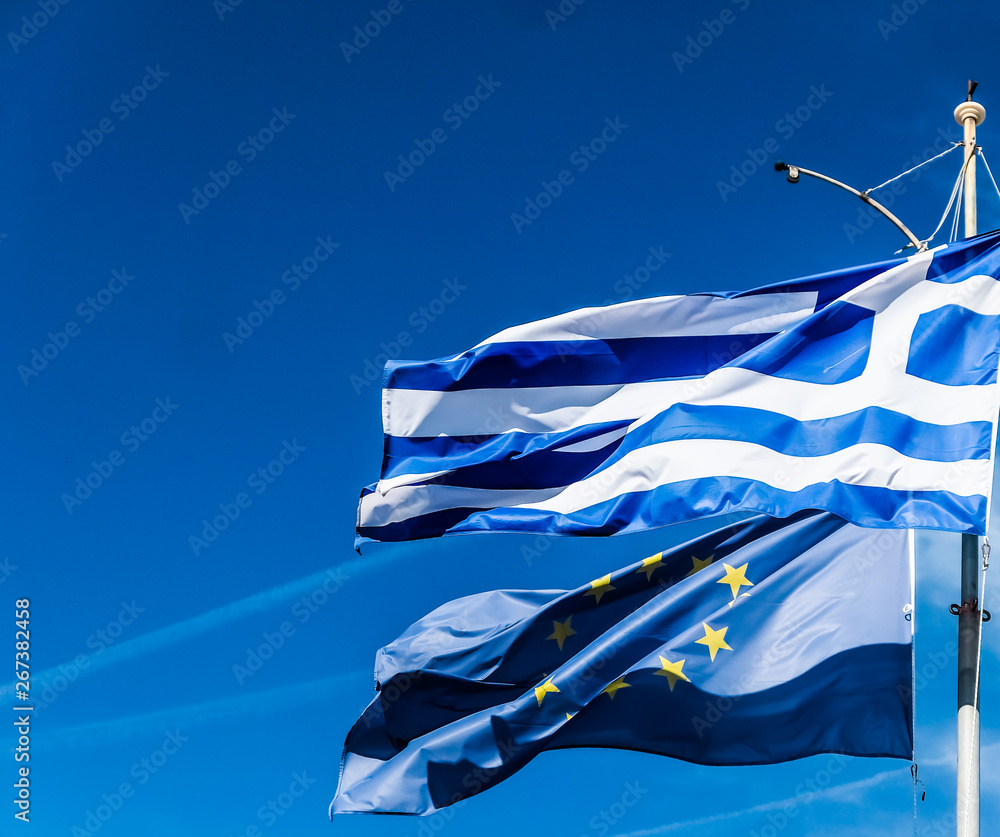 Flags of Greece and European Union on blue sky background, politics of ...